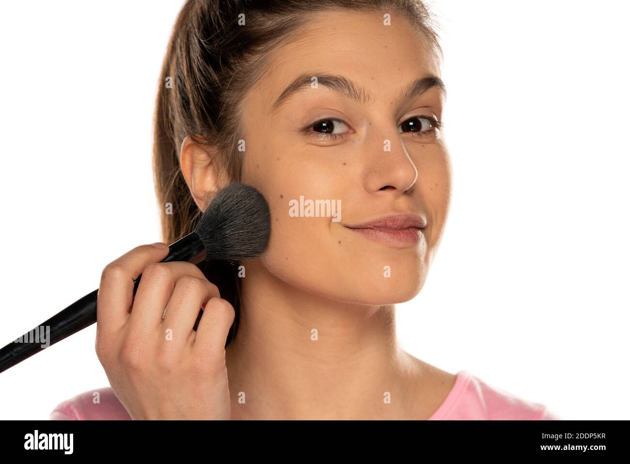 Portrait of young happy woman applying powder foundation with brush on ...