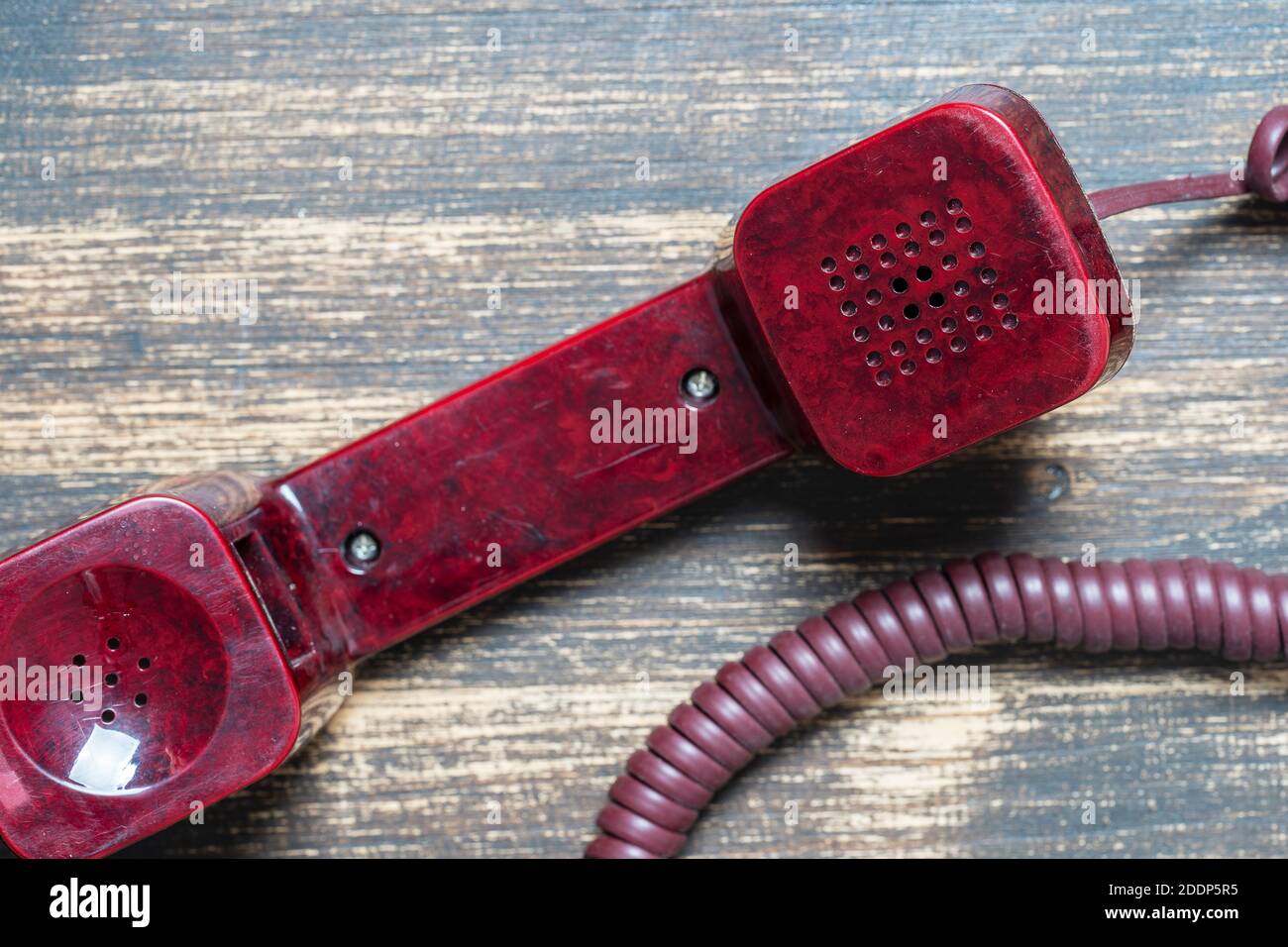 Vintage red old telephone receiver with cord on a wooden board, close ...