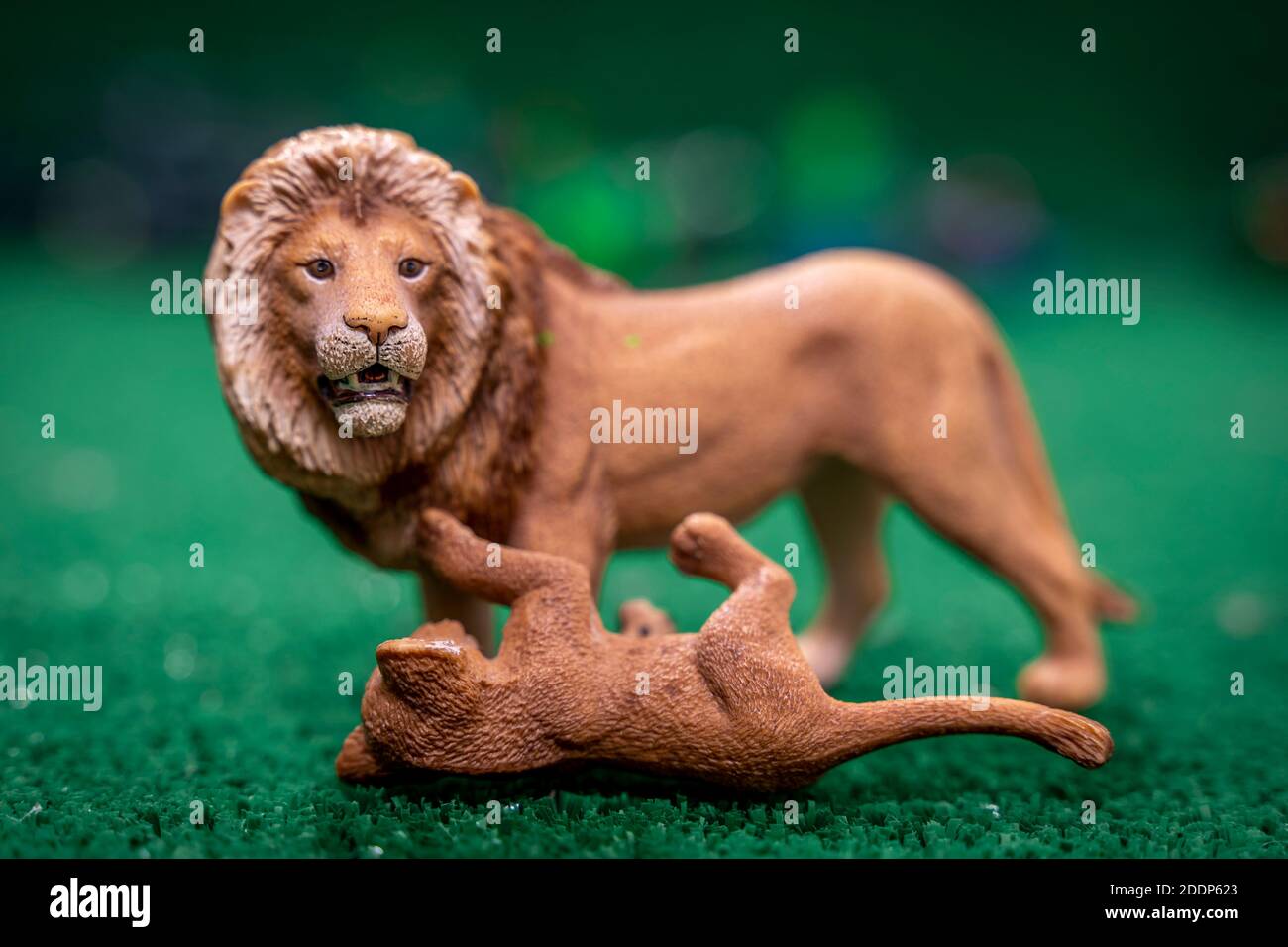 plastic figurines of lion playing with her cub in a savannah-like ...
