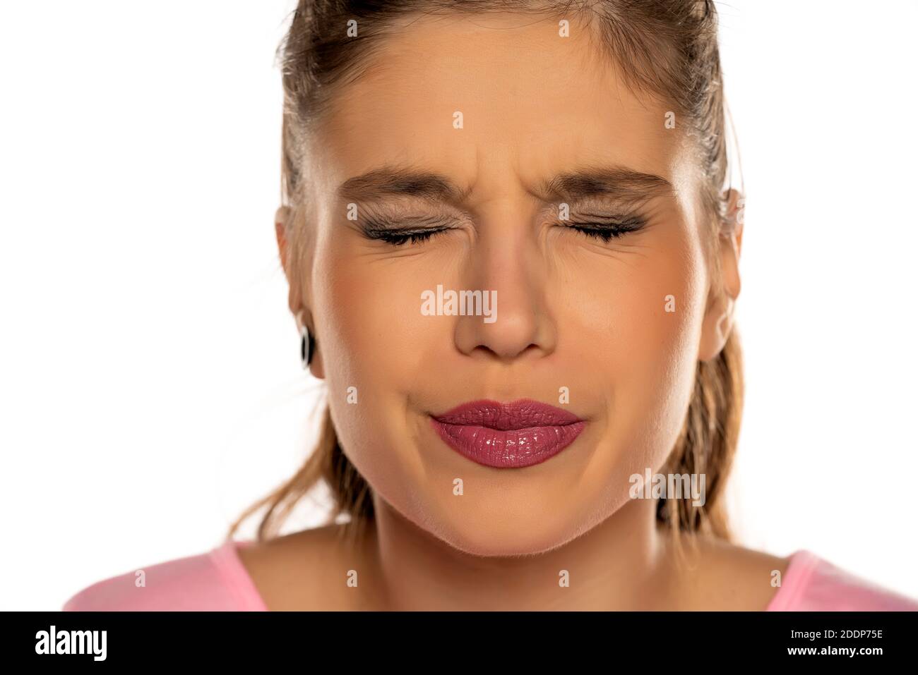 Portrait of young woman with painfully loock and closed eyes on white ...
