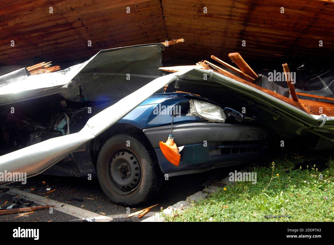 blue car destroyed by a collapsed wooden building, storm damage Stock ...