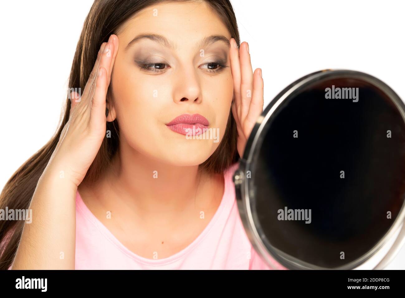 Young beautiful woman tightening her face with her hands in front the ...