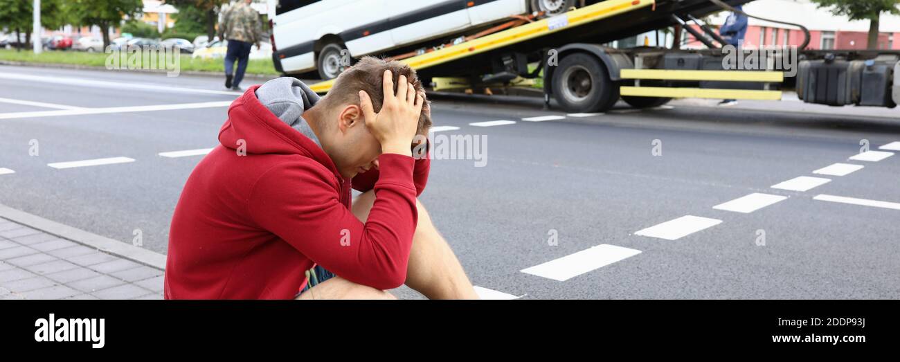 Minivan driver sits on side of road and holds his head during ...