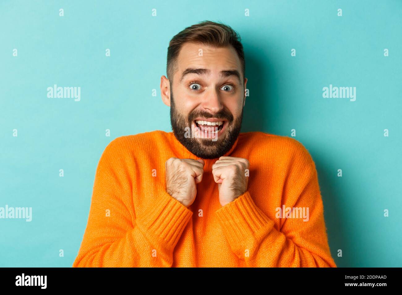 Close-up of startled man gasping and pressing hands to chest, staring ...