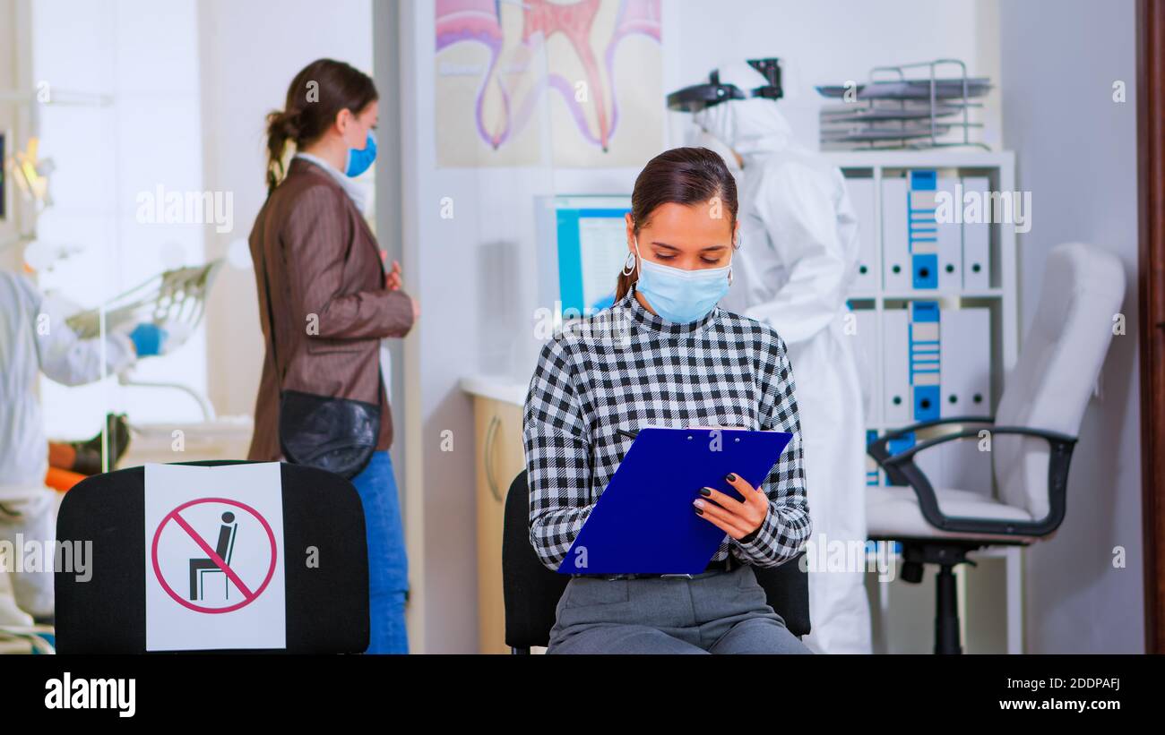 Patient with face protection mask writing on registration form in ...