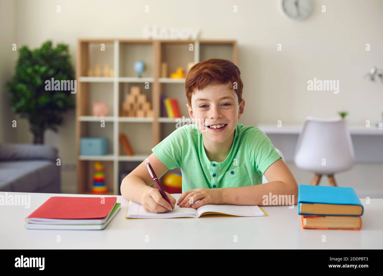 Online school. Smiling boy sitting at desk with notebooks and textbooks ...