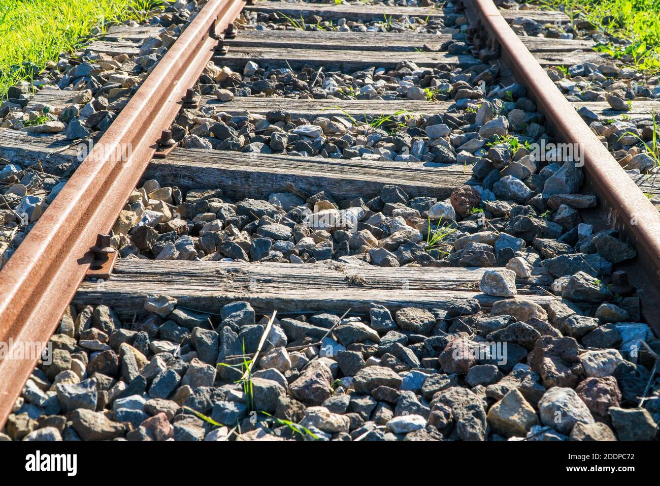 Old rusty rails with wooden slats on rocky floor Stock Photo - Alamy