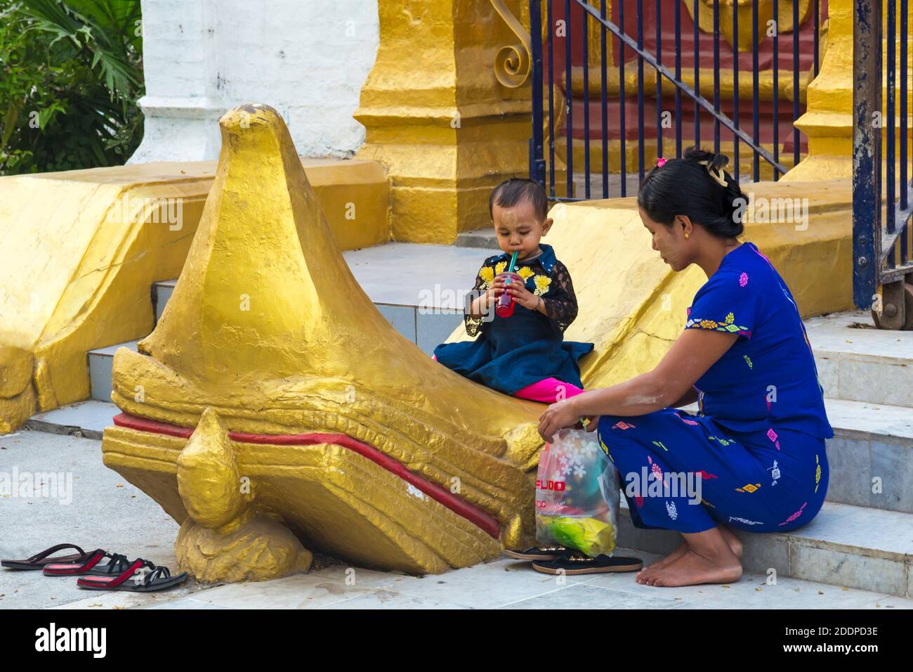 Young woman with child girl having a drink with thanaka on cheeks at ...