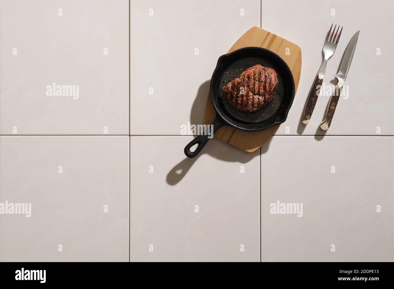 Top view of grilled beef steak in cast iron skillet on ceramic tile ...