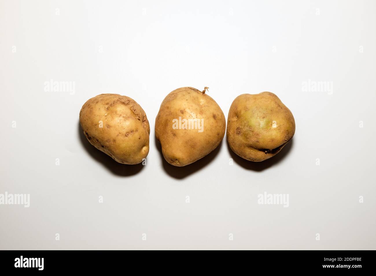 Three potatoes on a white background Stock Photo - Alamy