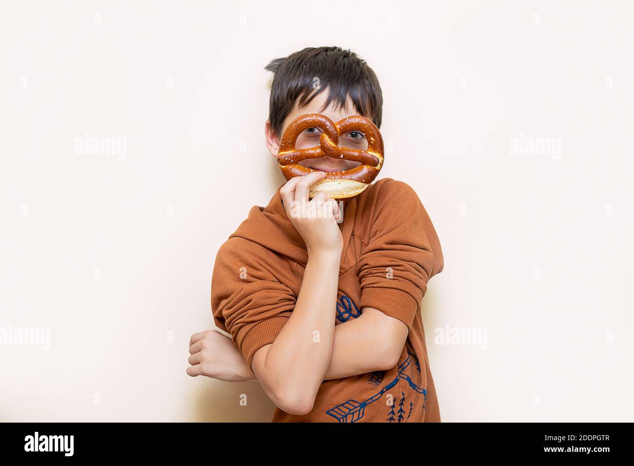 An appetizing Bavarian pretzel in the hands of a teenage boy. Looks ...