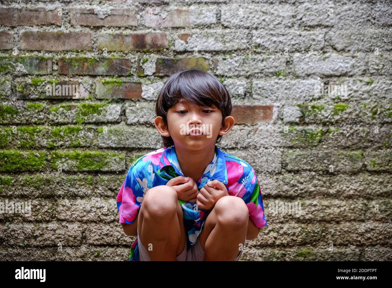 Southeast Asian Little Boy with Sad or Bored Expression. Rustic Brick ...
