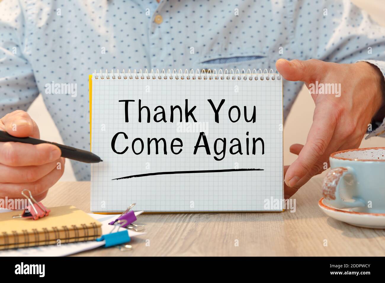 Notebook with the text Thank You Come Again on the office table among ...