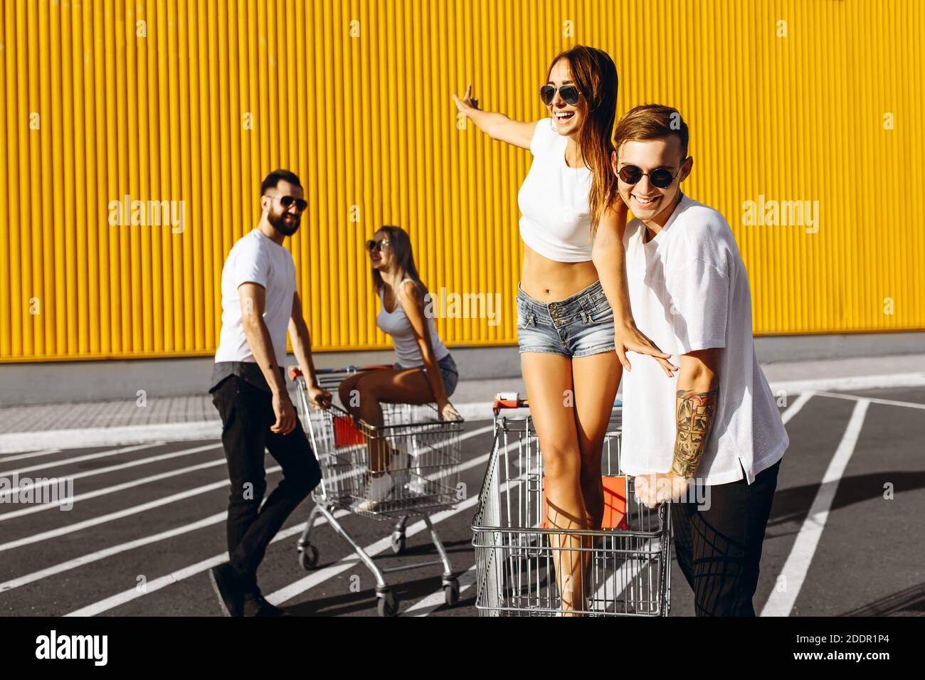 A group of happy young people, men and women, having fun on trolleys ...