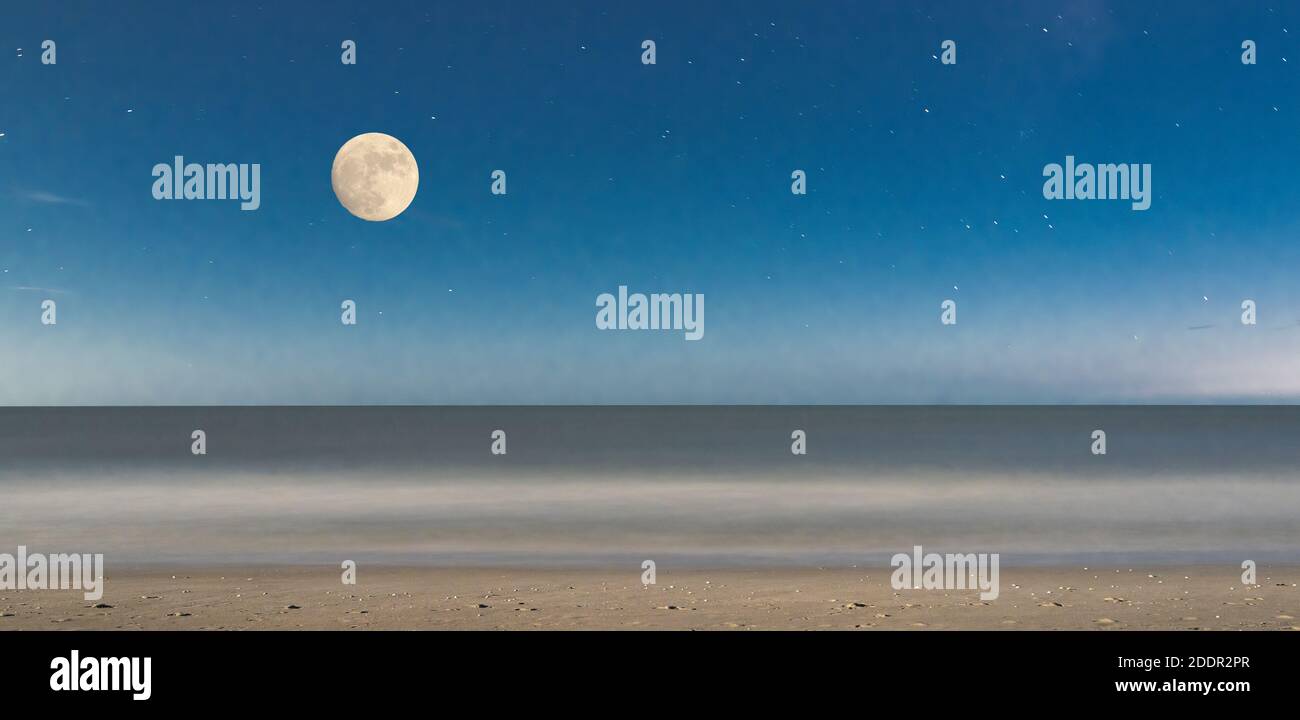 Abstract view of full moon over smooth blurred Gulf of Mexico at night ...