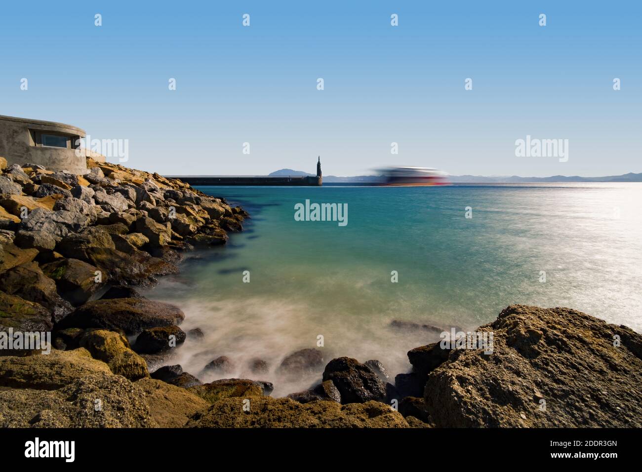 A closeup of stones at the seaside with a concrete construction on the ...