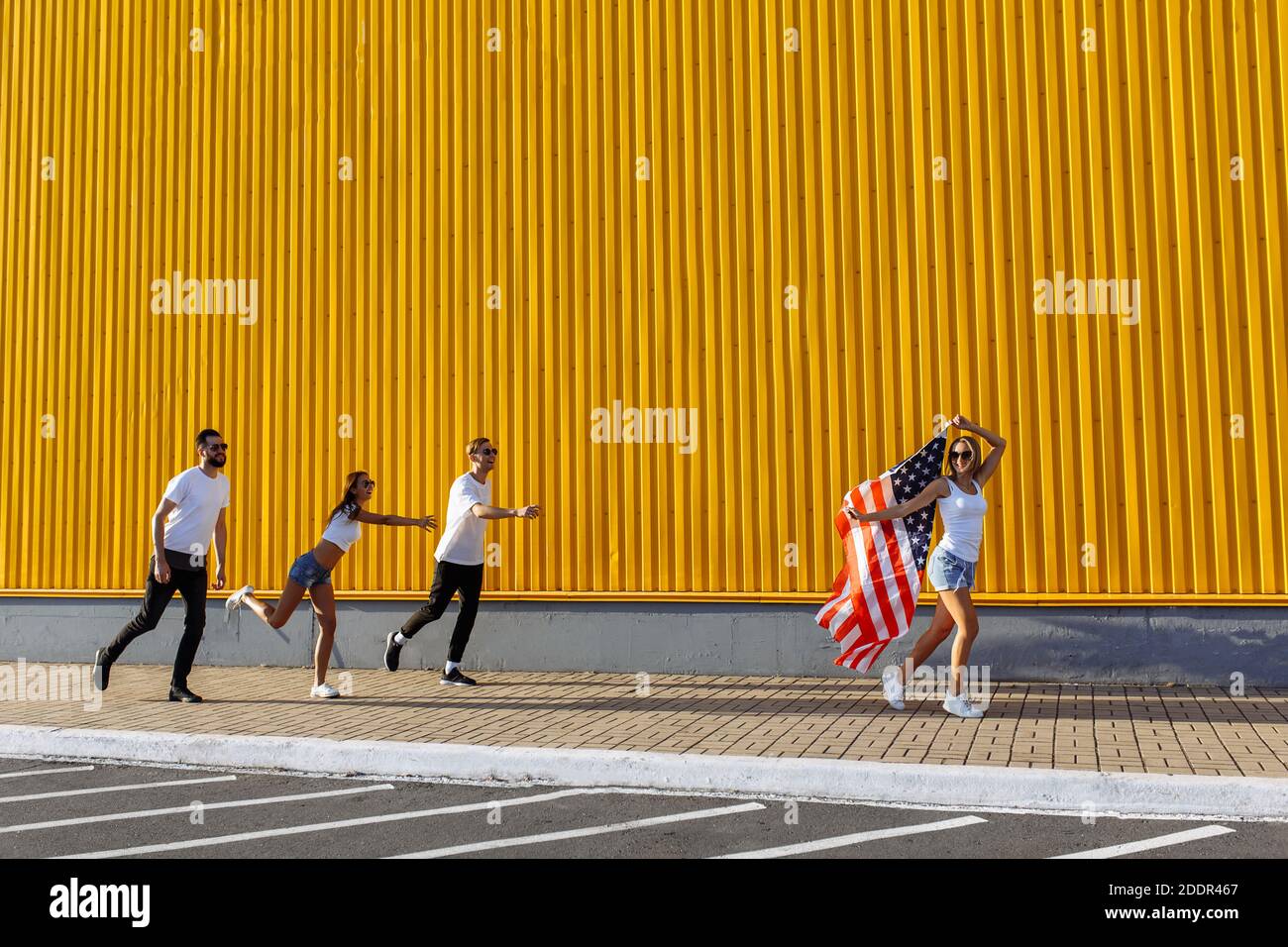 A group of young friends, with an American flag, have fun and run ...