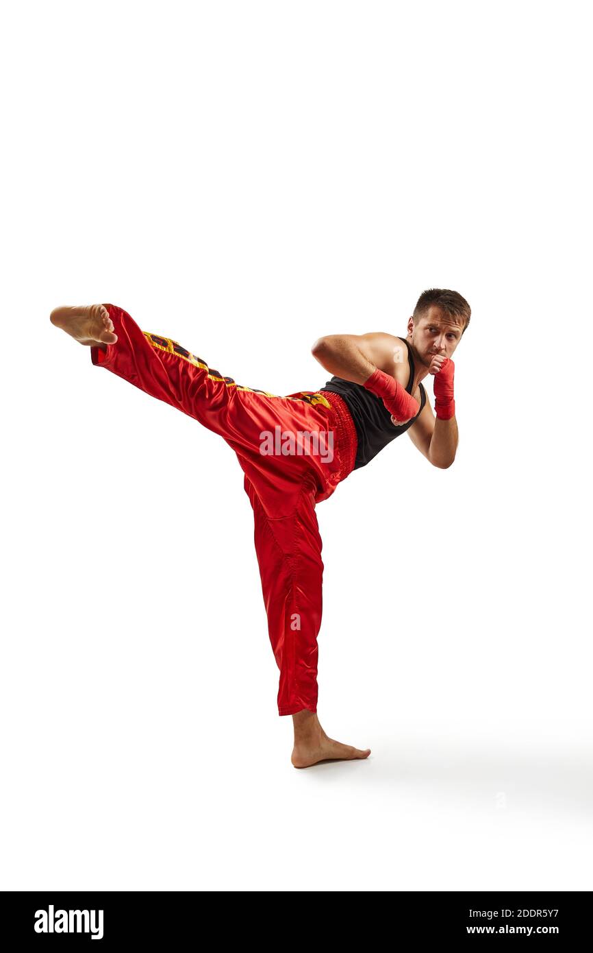 Athletic man in red sports bandages on his hands making kick during ...