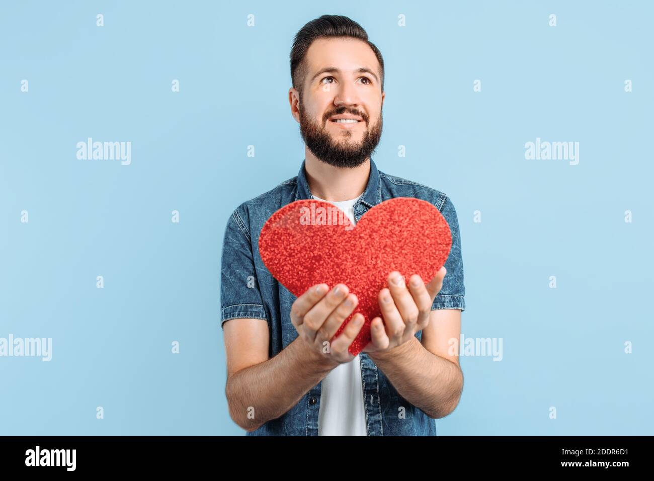 Love and Valentine's day an attractive man with a beard holds a red ...
