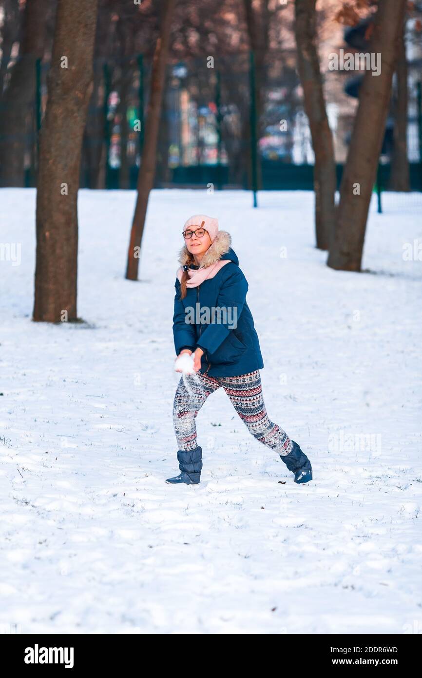 Happy teenage girl having a snowball fight, ready to throw a snowball ...