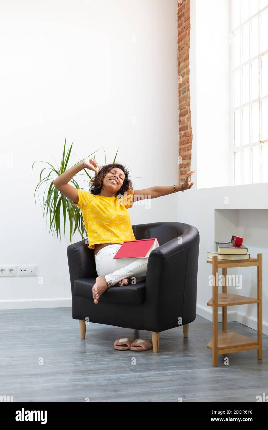 Brunette woman takes a break while reading and stretches her arms ...