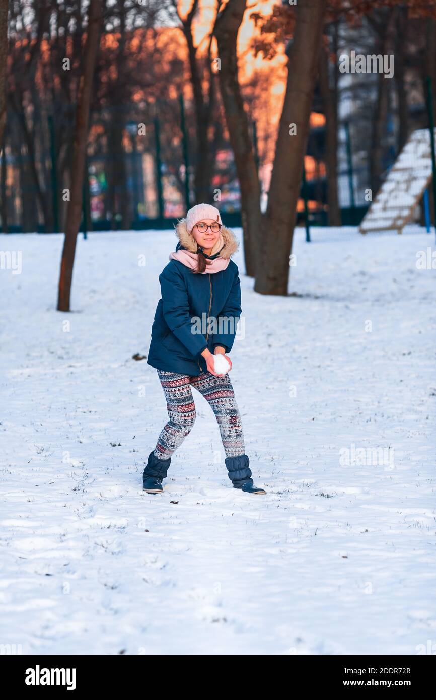 Happy teenage girl having a snowball fight, ready to throw a snowball ...