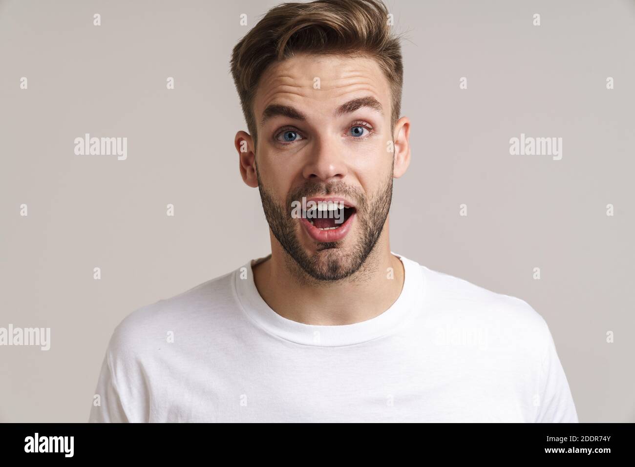Excited handsome guy expressing surprise at camera isolated over grey ...