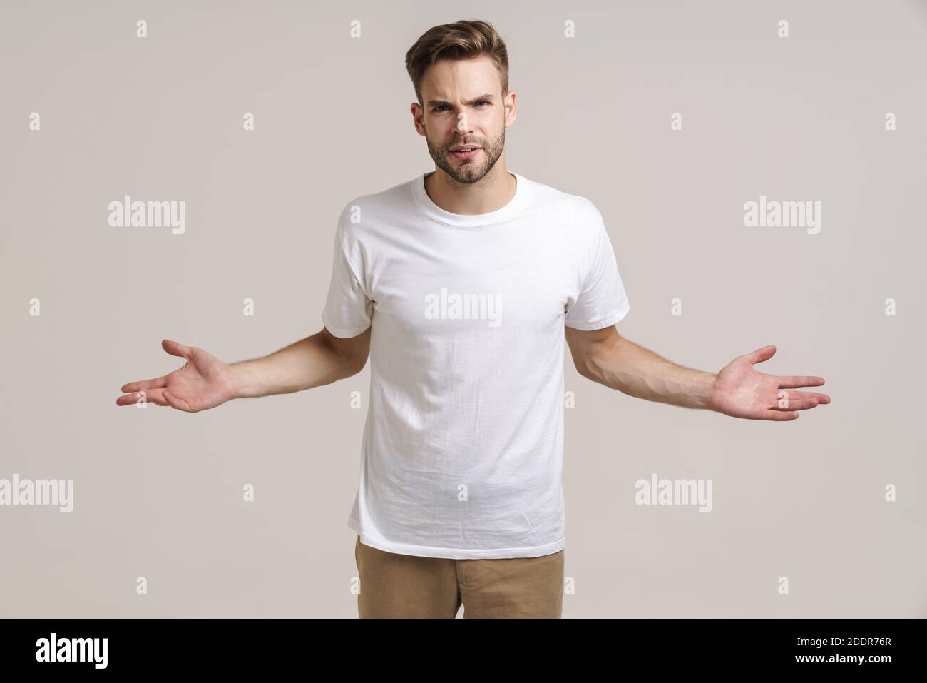 Displeased handsome blonde guy posing with throwing up hands isolated ...