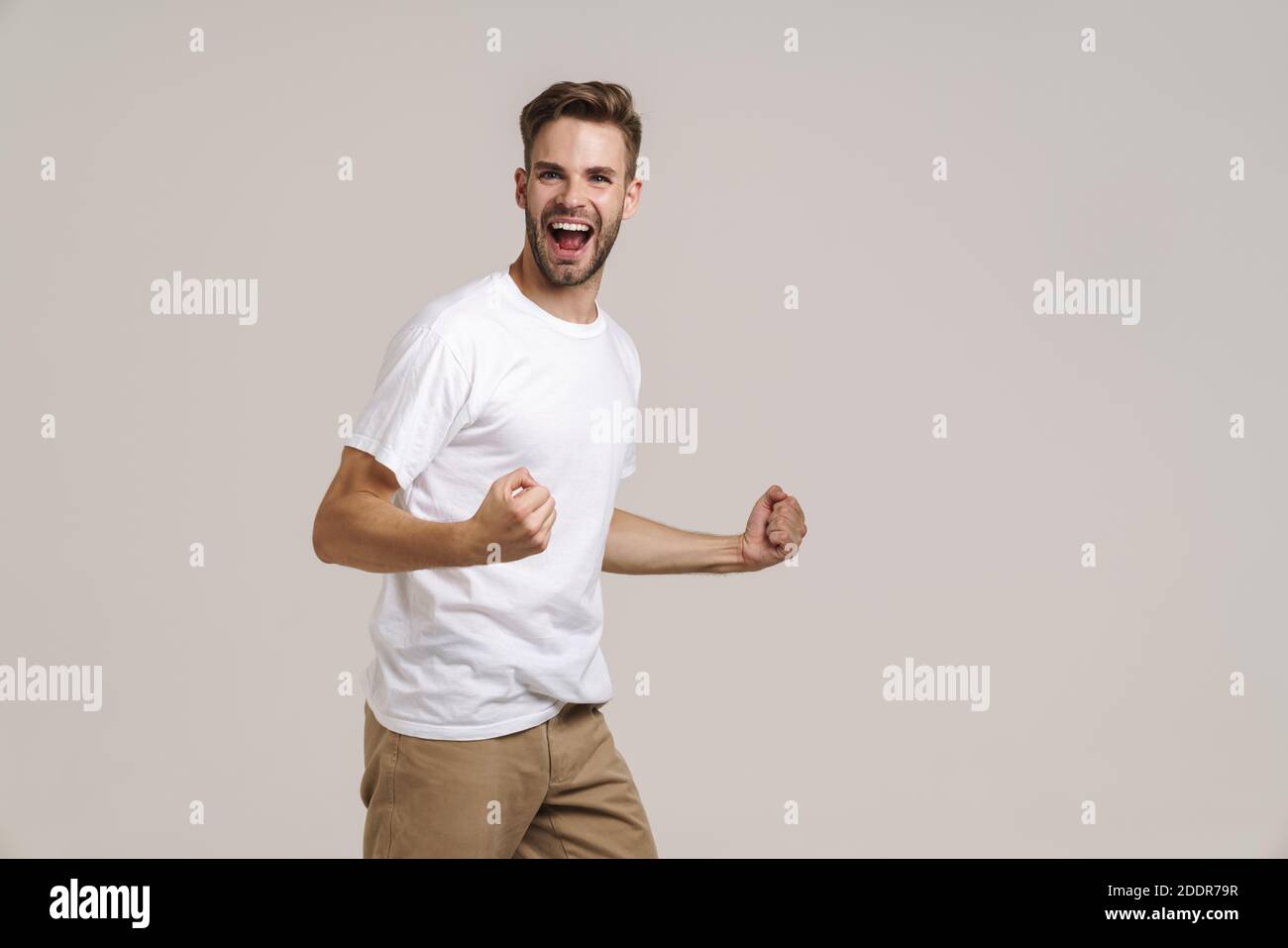 Delighted handsome guy screaming and showing winner gesture isolated ...