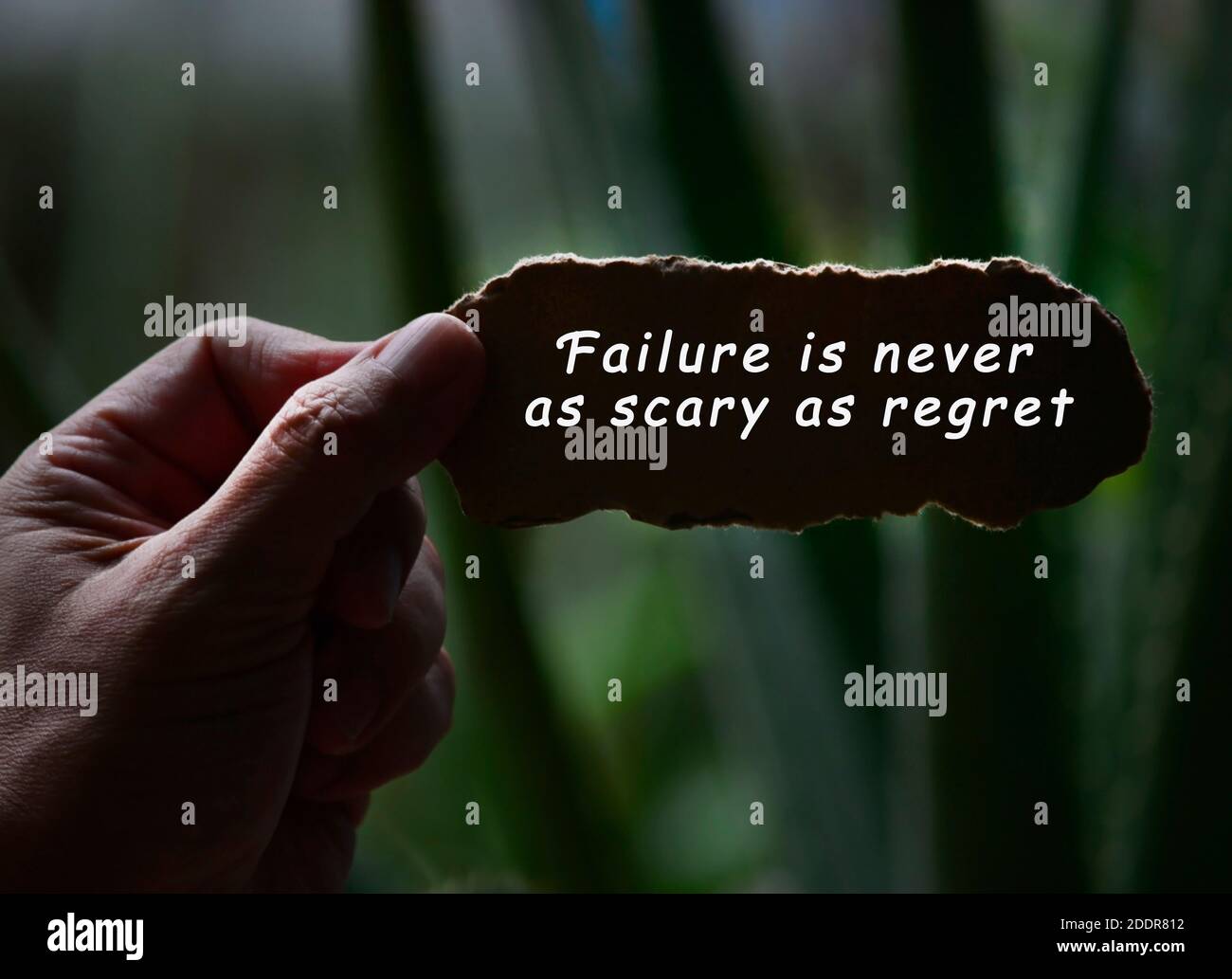 Hands holding torn paper with motivational quote and blurred dark ...