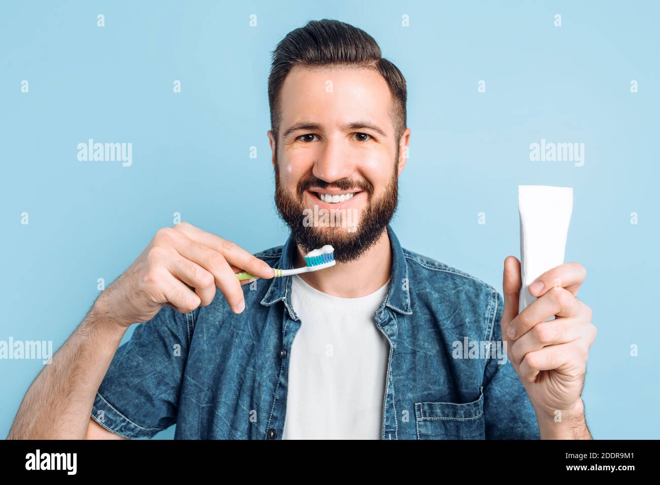 Happy young man with bristles, holding a brush and a tube of toothpaste ...