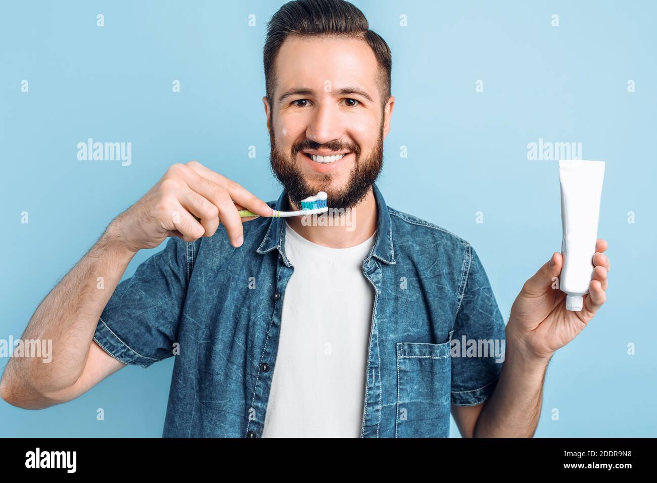 Happy young man with bristles, holding a brush and a tube of toothpaste ...
