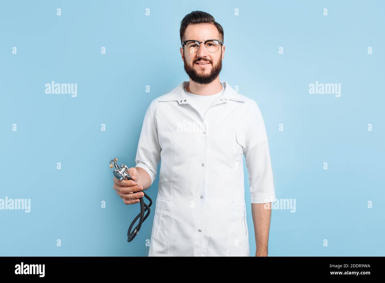 A young Intern doctor with a stethoscope in his hands stands on a light ...