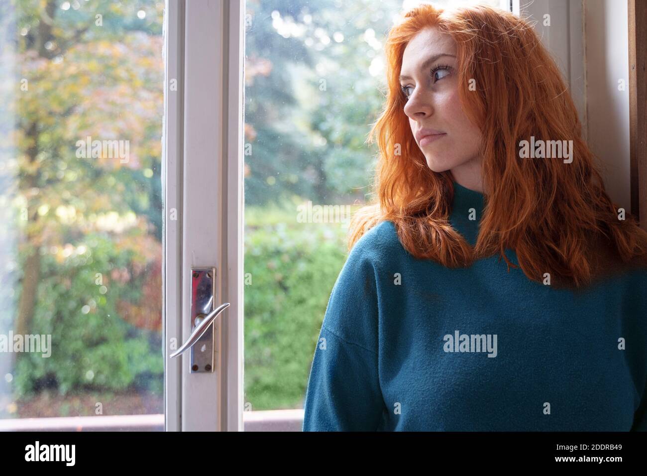 Portrait of pensive woman standing beside window Stock Photo - Alamy