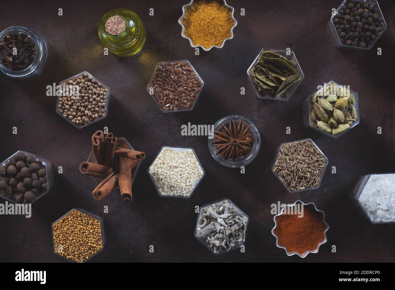 Various spices in hexagonal jars appear on a metal rusty baking sheet ...