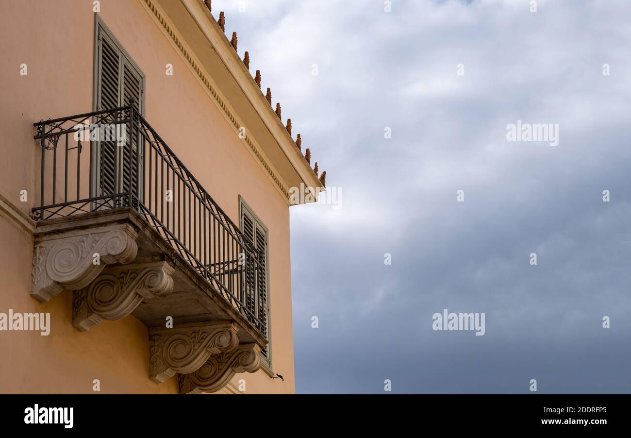 Neoclassical building facade with balcony detail, cloudy sky background ...