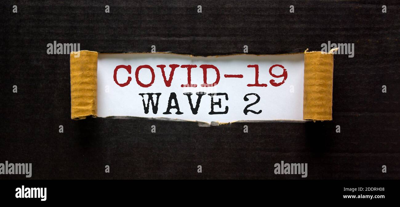 Covid-19 wave 2. The words 'covid-19 wave 2' appearing behind torn ...