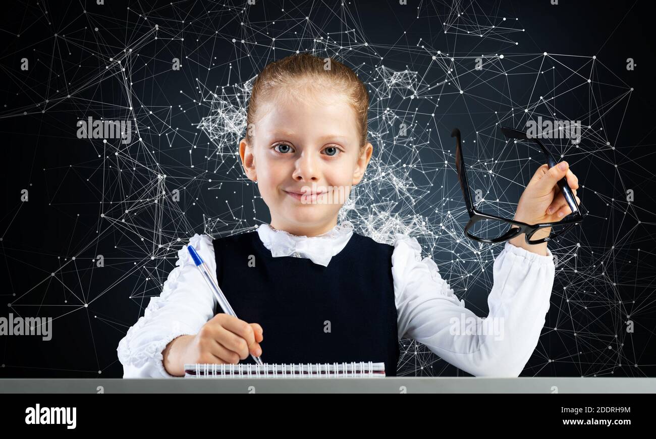 Smiling little girl in schoolwear doing homework Stock Photo - Alamy