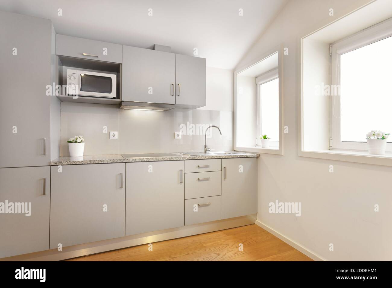 Small and modern kitchen facing two bright windows Stock Photo - Alamy
