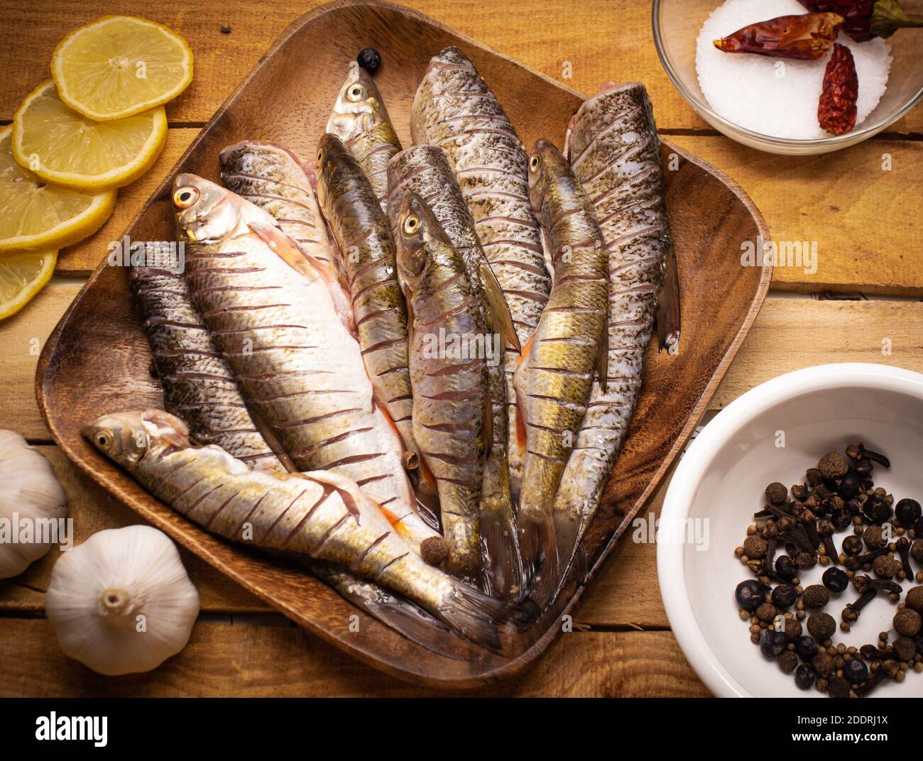 Top view fresh fish chub on a wooden squared brown plate on the wooden ...