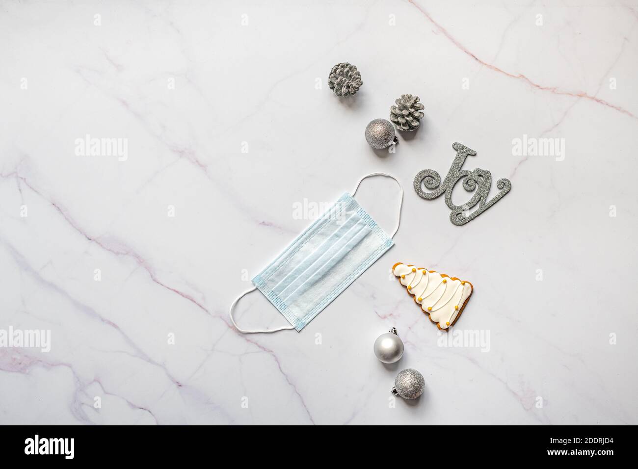 A top view of face mask and Christmas ornaments on white marble surface ...