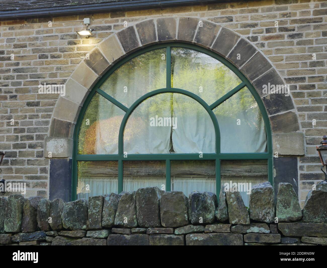 Large arched window with green frame in stone building with outside ...