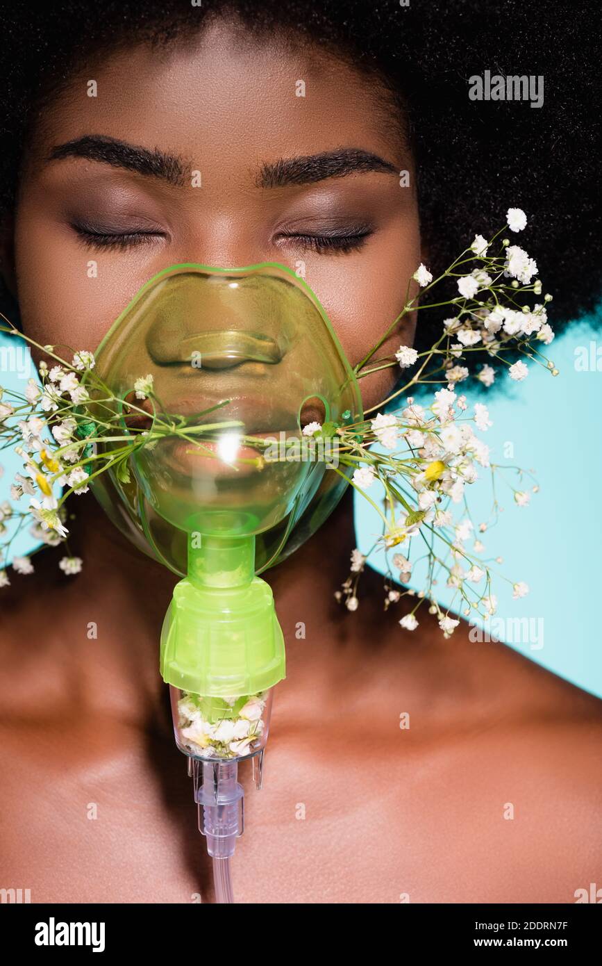 african american young woman with flowers in inhaler isolated on blue ...