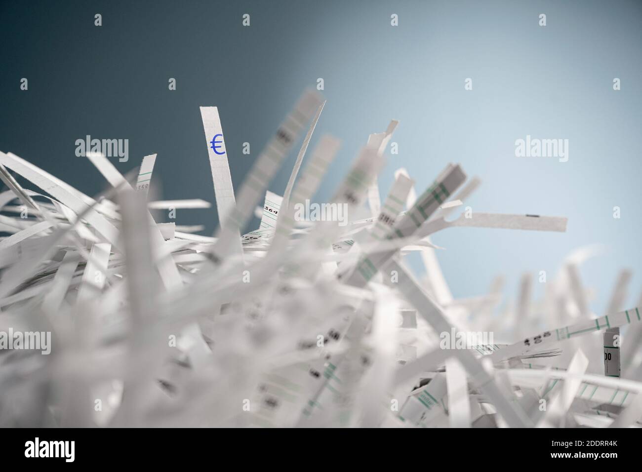 A pile of shredded paper strips and on one strip a Euro symbol is ...