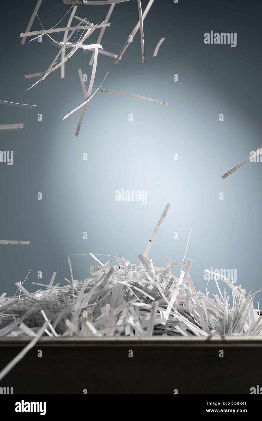 A pile of shredded paper strips lie in a metal box and from above, more ...