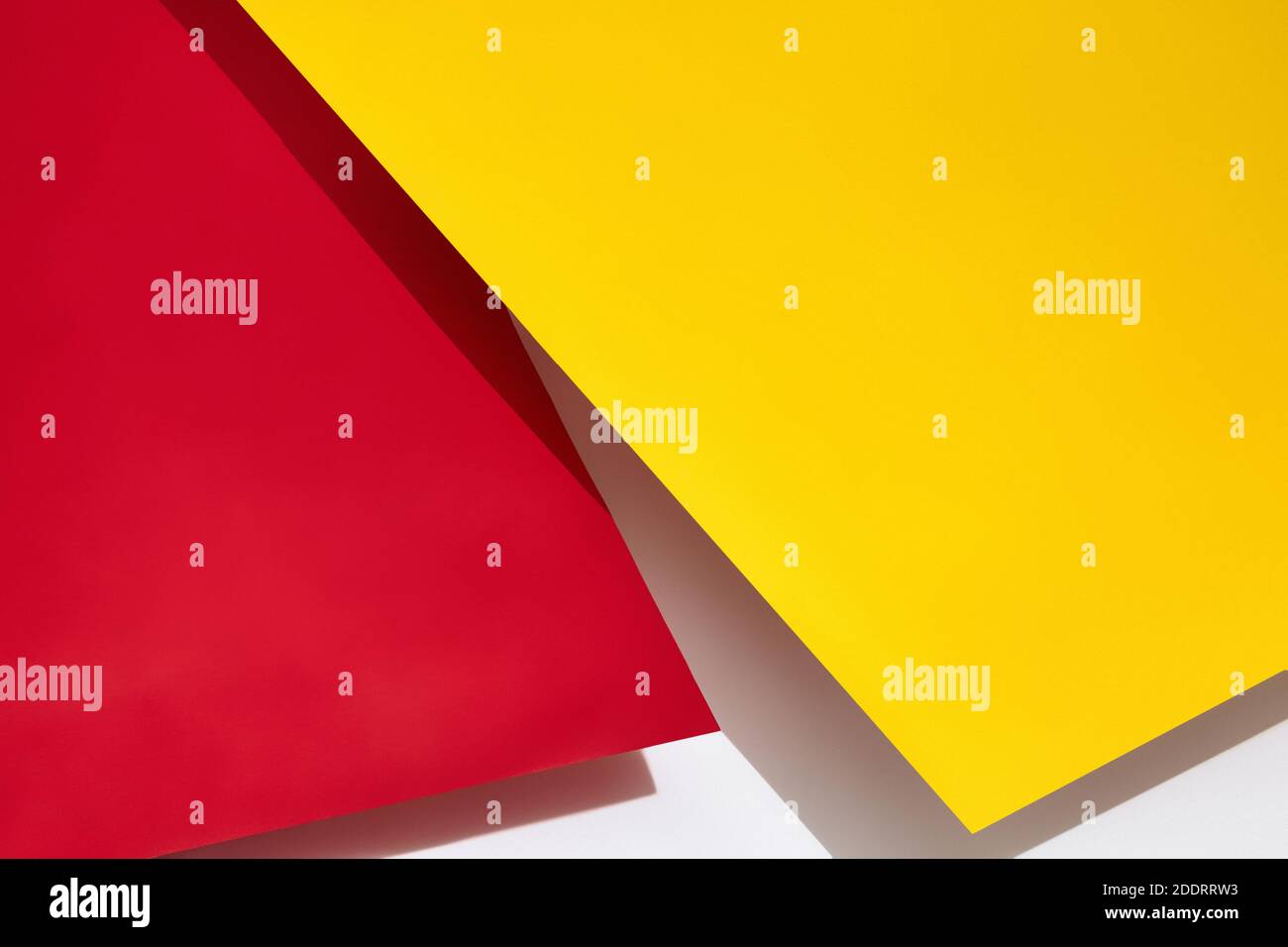 Red and yellow shadow-casting sheets of paper or stands above white ...