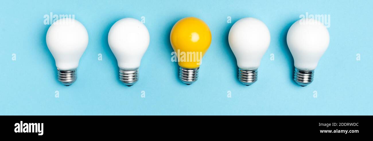 top view of white and yellow light bulbs on blue background, banner ...