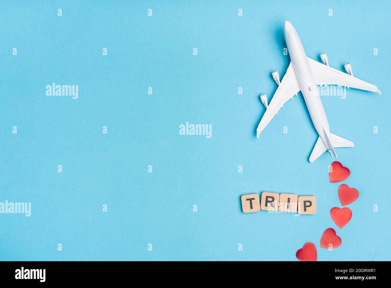 top view of plane model, word trip and red hearts on blue background ...
