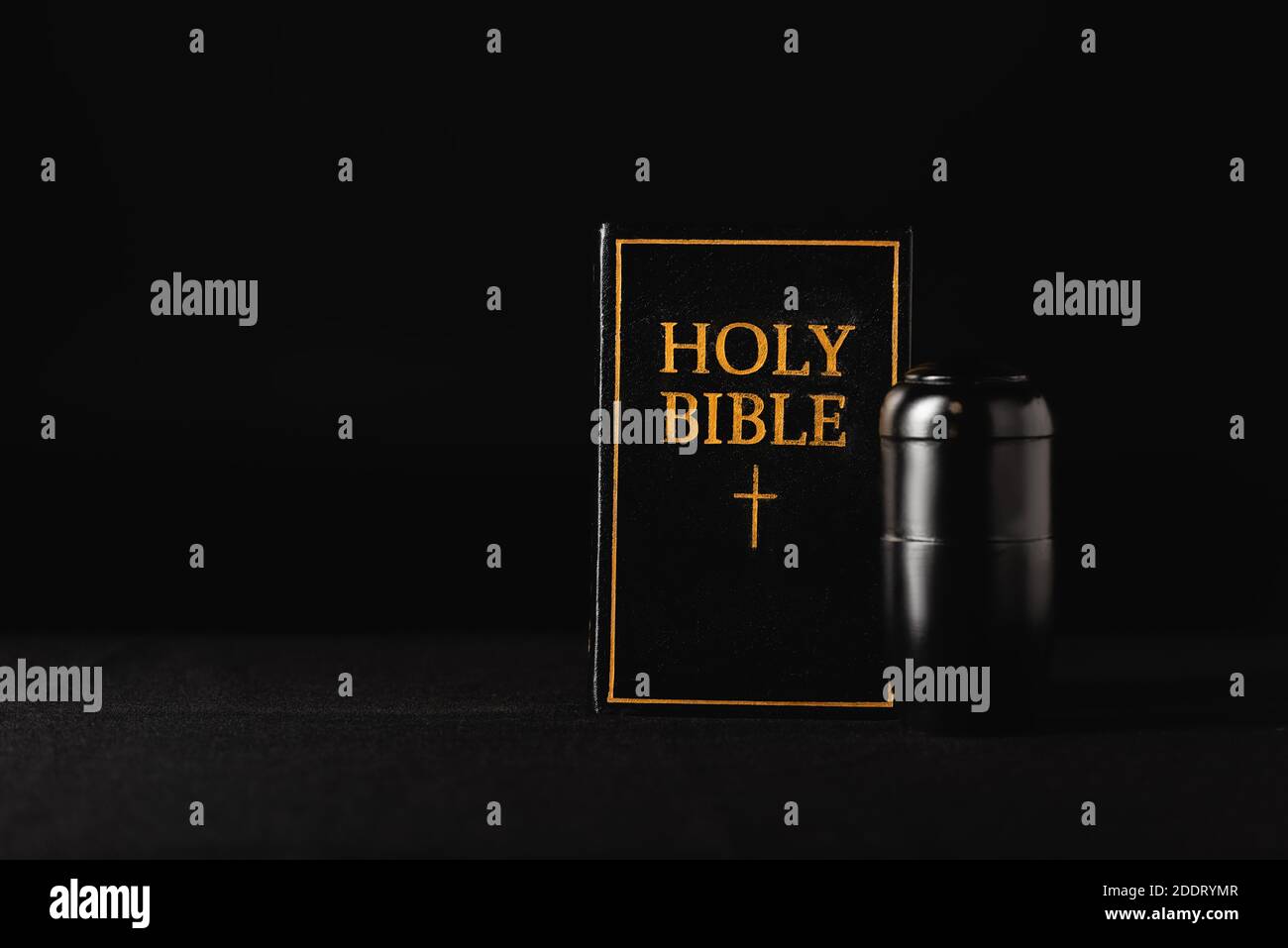 holy bible and urn with ashes on black background, funeral concept ...