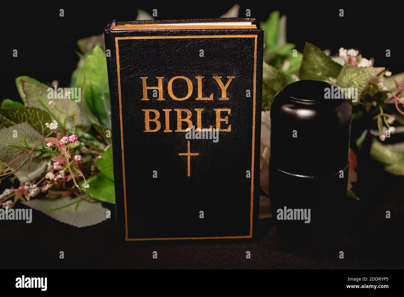 holy bible and urn with ashes on black background, funeral concept ...